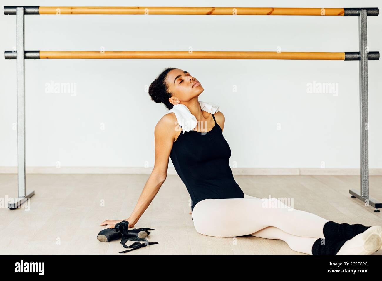 Young ballerina resting after dance training in the studio. Woman with ...