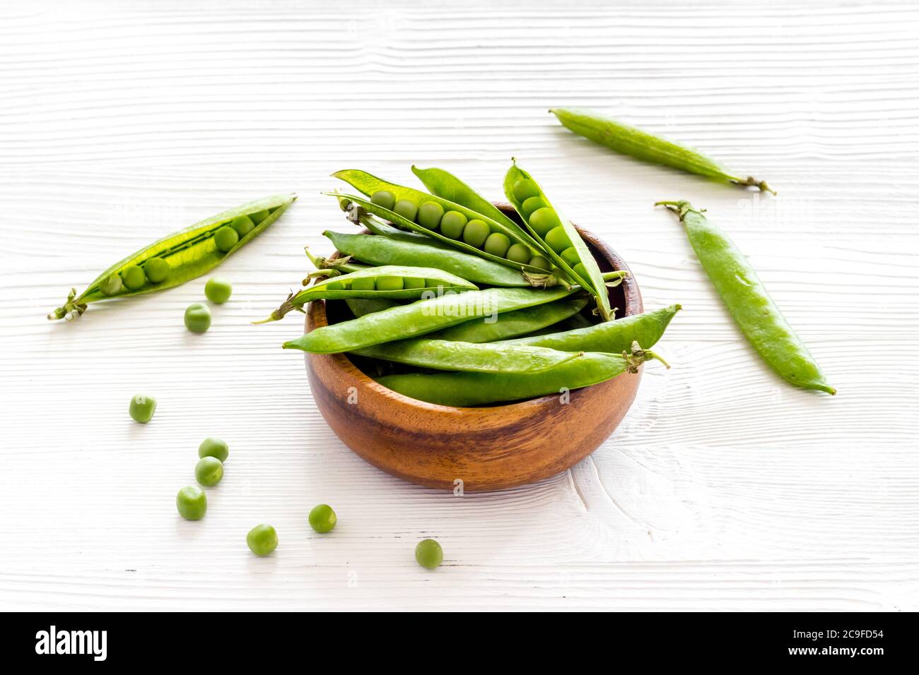 Green pea pods in wooden bowl on the kitchen background Stock Photo - Alamy