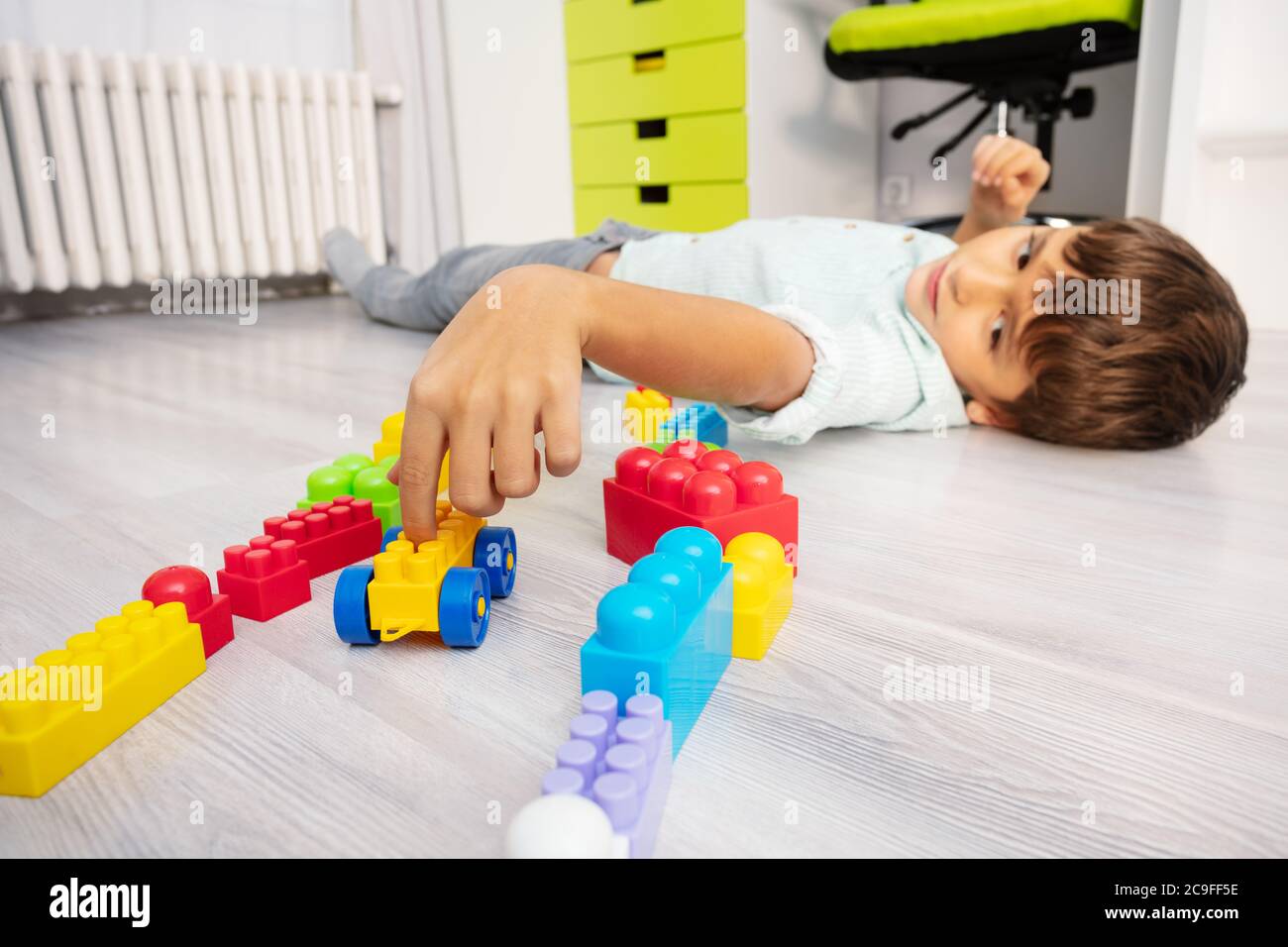 Special child, playing with blocks and cars laying on the floor focus ...