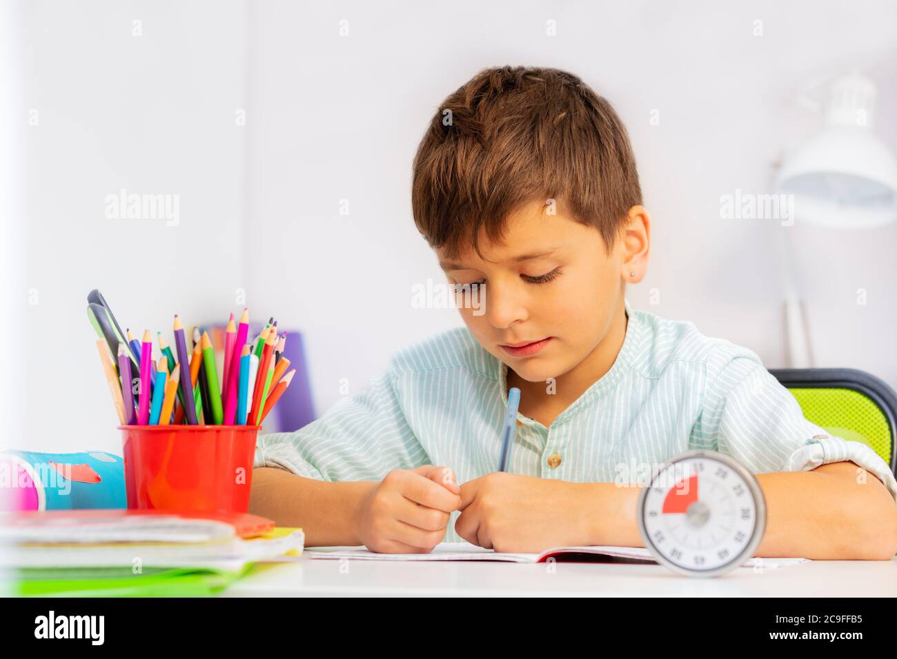 Little boy doing writing exercise with lesson timer Stock Photo - Alamy
