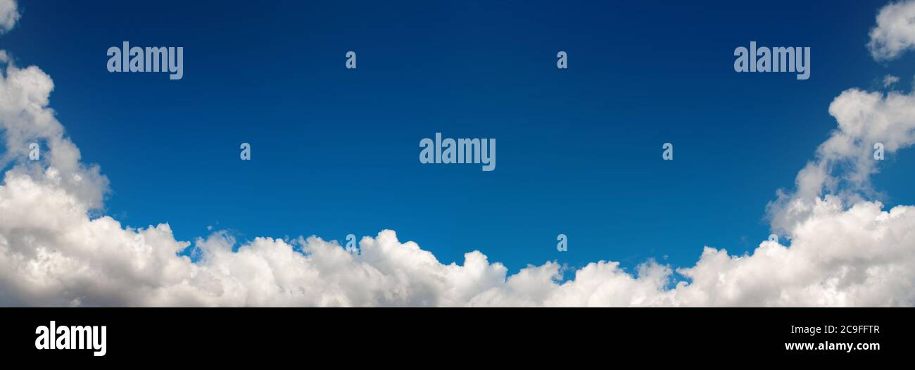 Deep blue sky with frame-shaped clouds. Cloudy skyscape banner with a ...