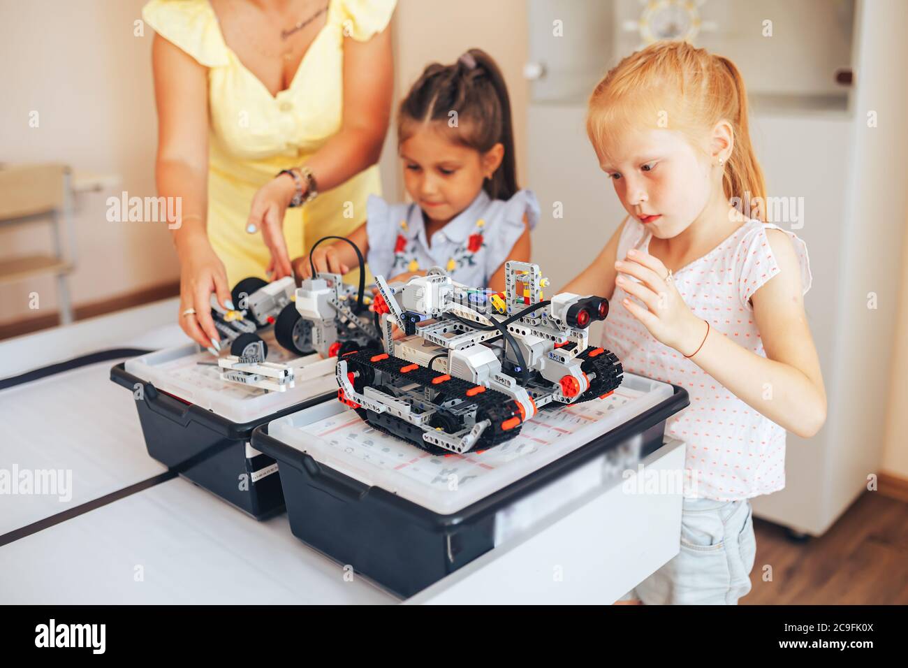 Two schoolgirls study in a robotics class, assemble a robot constructor ...