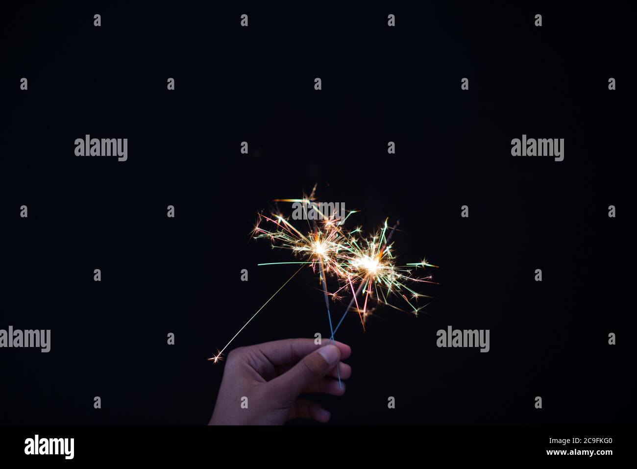 Person holding sparklers in hand against dark background Stock Photo ...