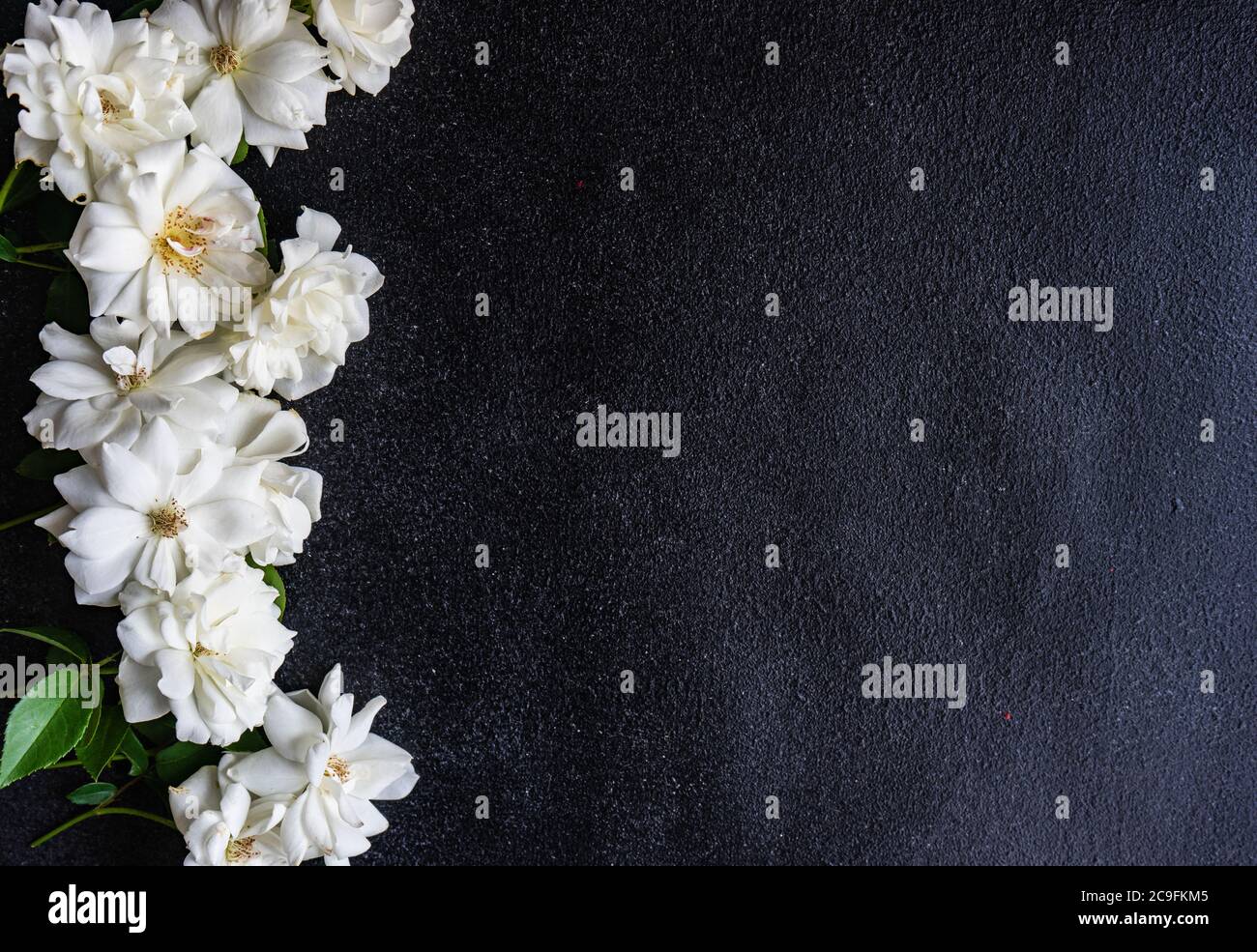 Frame with white rose flowers on stone dark background with copy space ...
