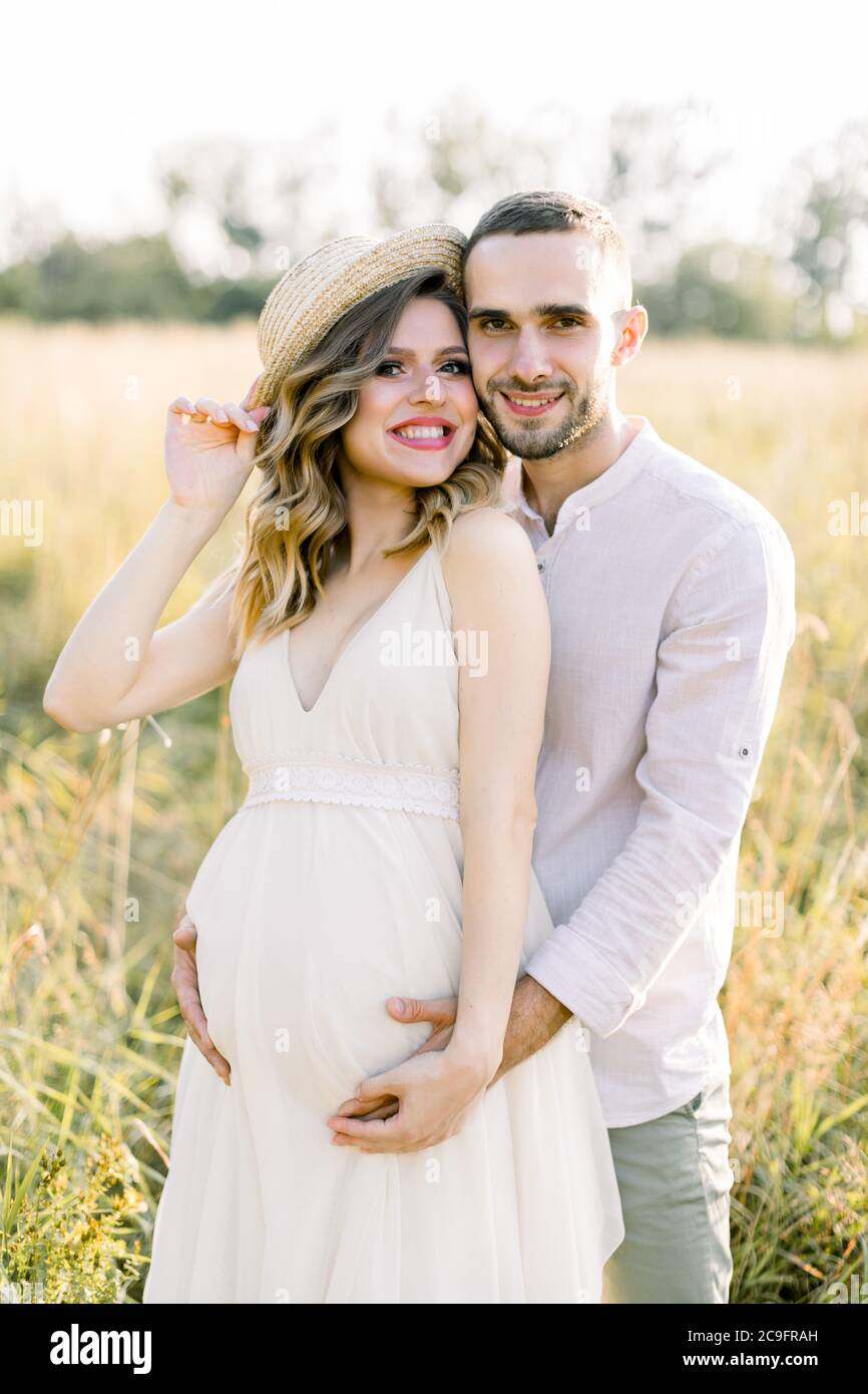 Lovely smiling happy pregnant couple in field at sunset, hugging the ...