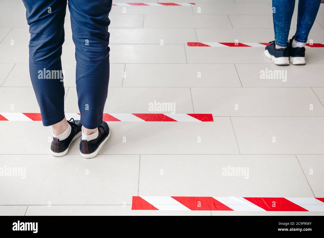 People stand in line keeping social distance, standing behind warning ...