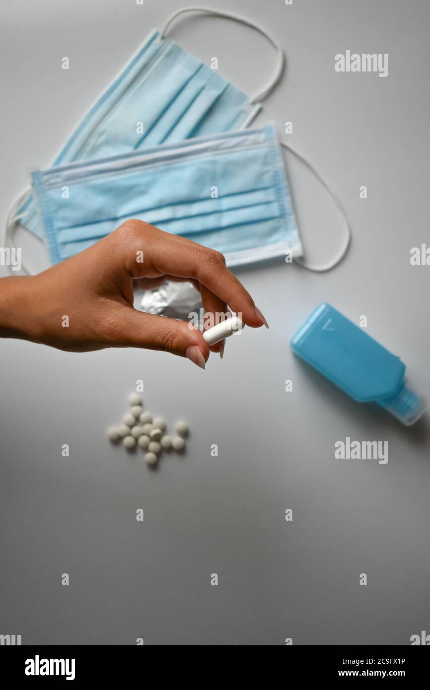 Vertical shot of hand holding a capsule over surface with pills ...