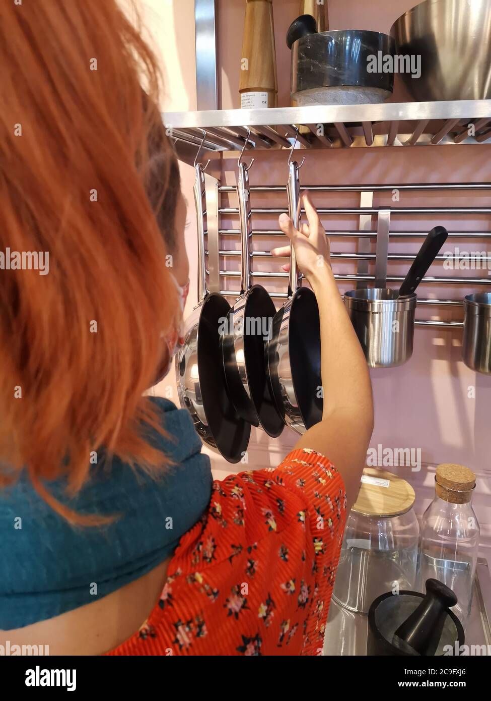 Vertical back view of a female reaching for pans to cook a meal Stock ...