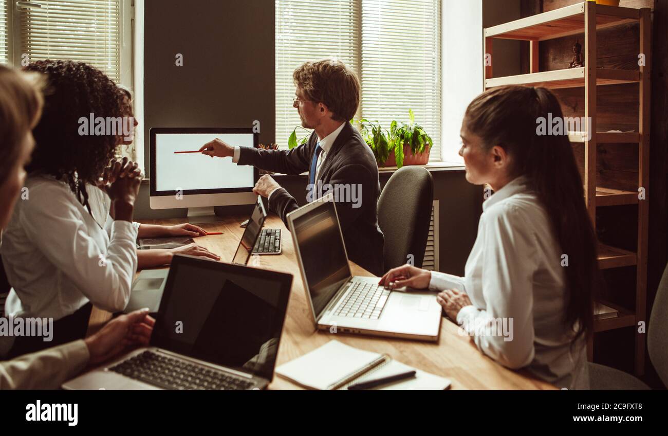 Project presentation. Businessman points to white screen of computer ...
