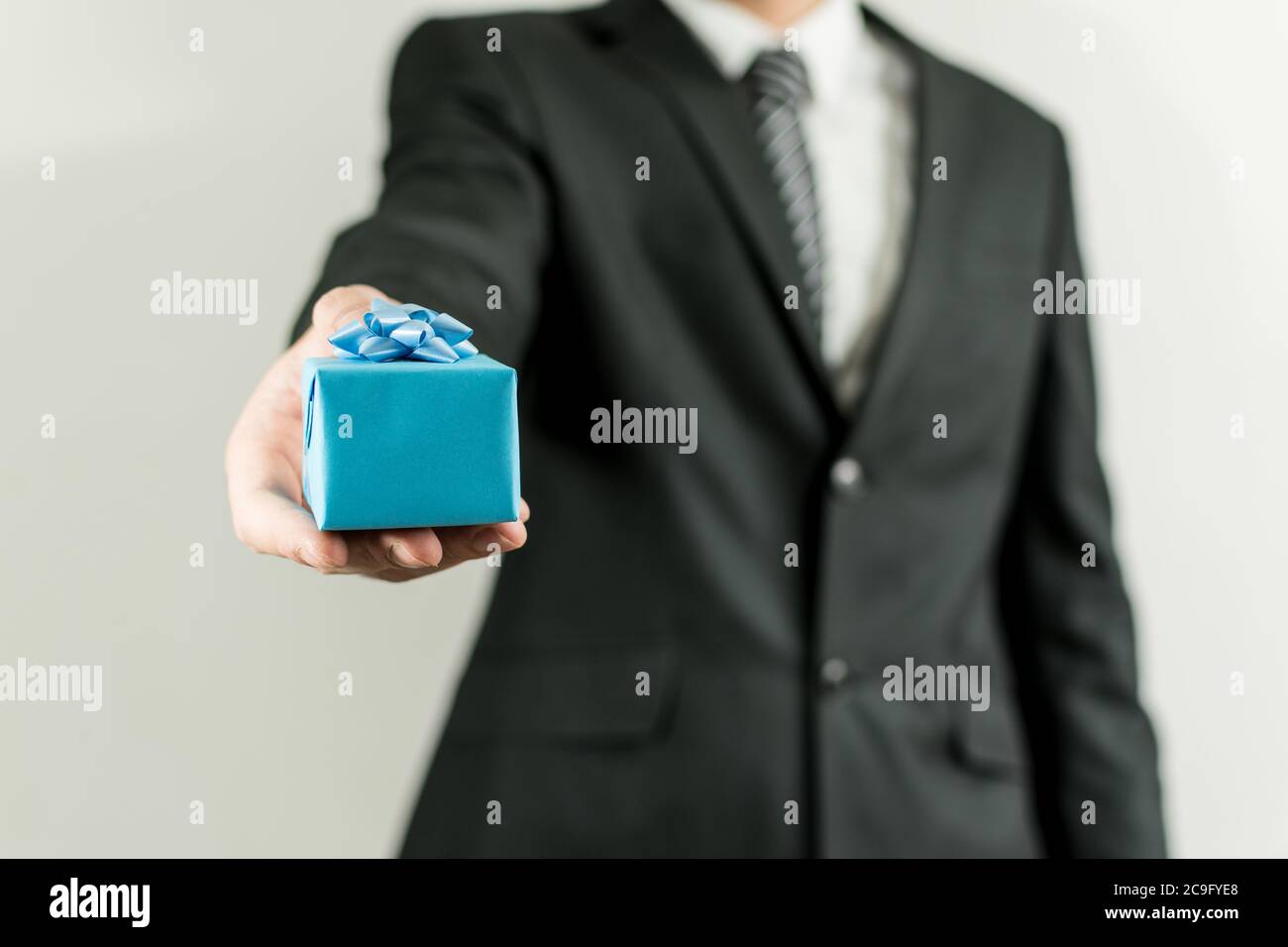 Hand holding a blue gift box with a green ribbon hi-res stock ...