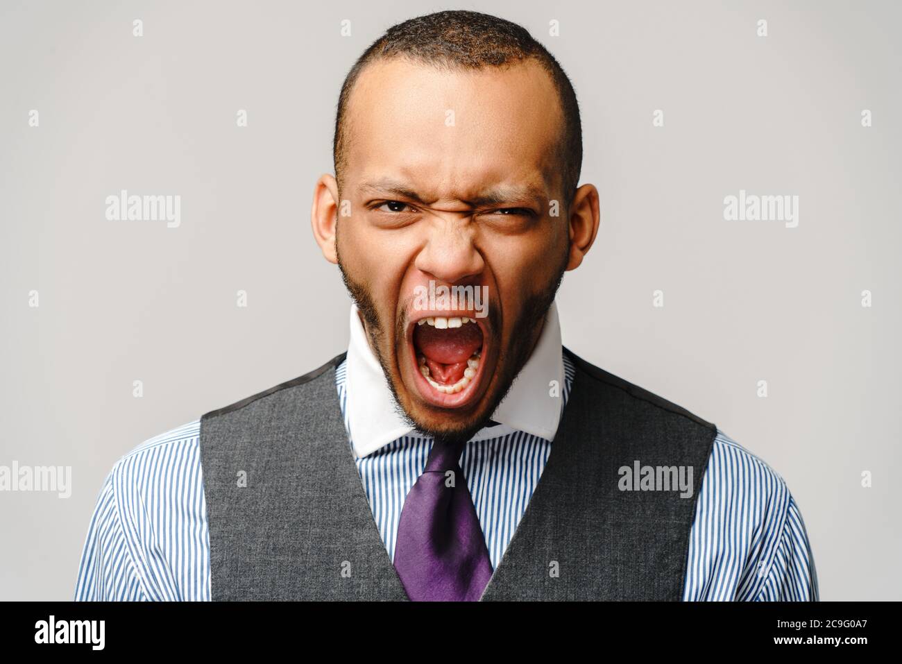 Angry african-american businessman in stress over light grey background ...