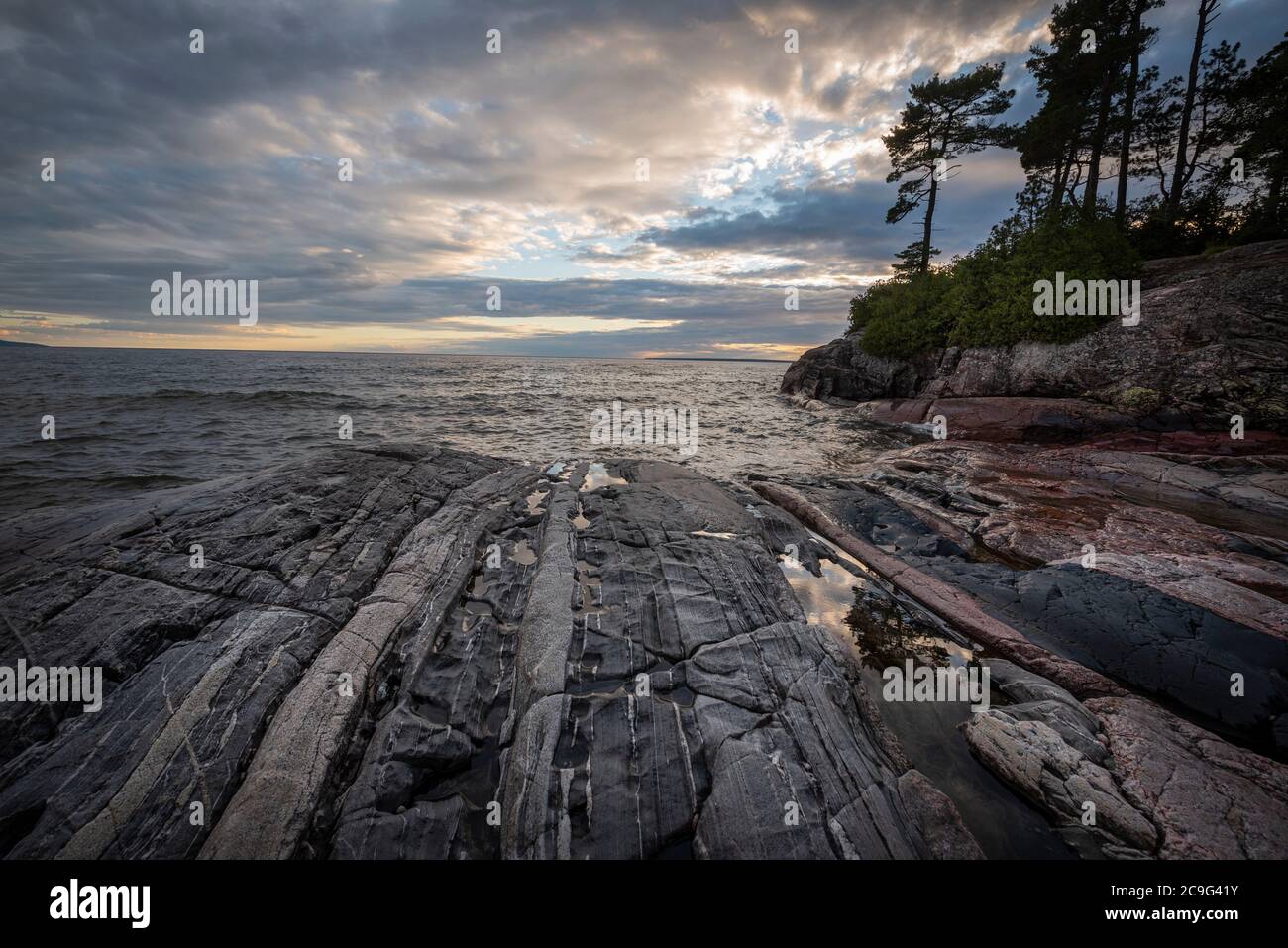Striated bedrock in multiple hues and types reach down to the water at ...
