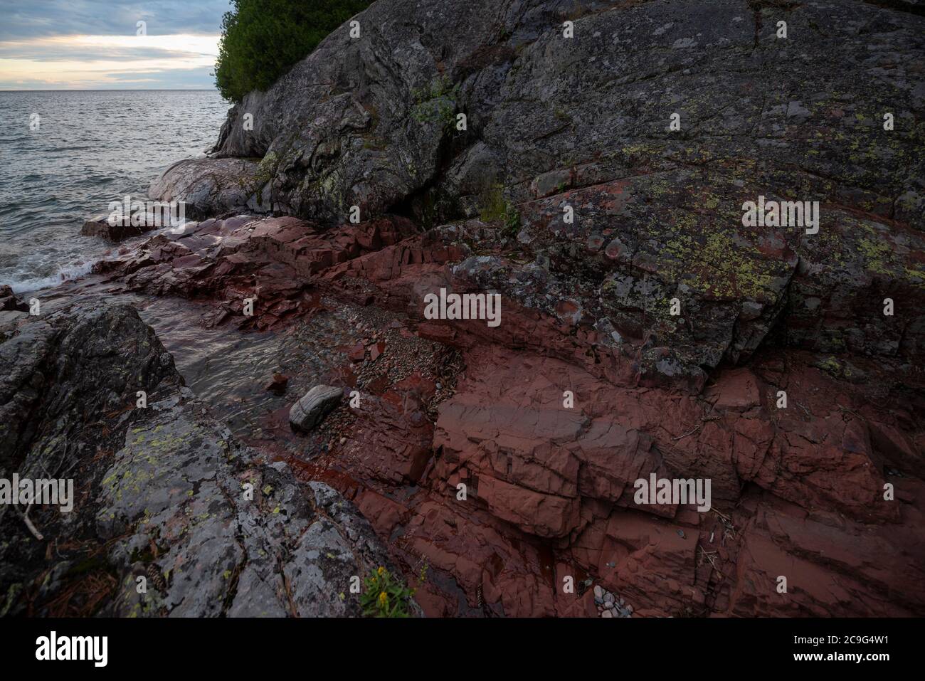 Red and grey mixed igneous rock lead down to the rough, northen shore ...