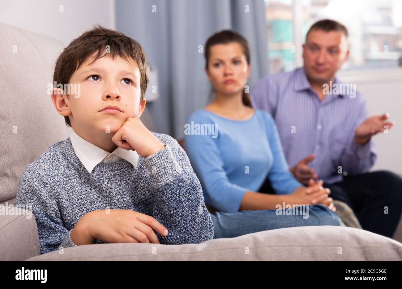 Portrait of upset preteen boy scolded by mother and father at home ...