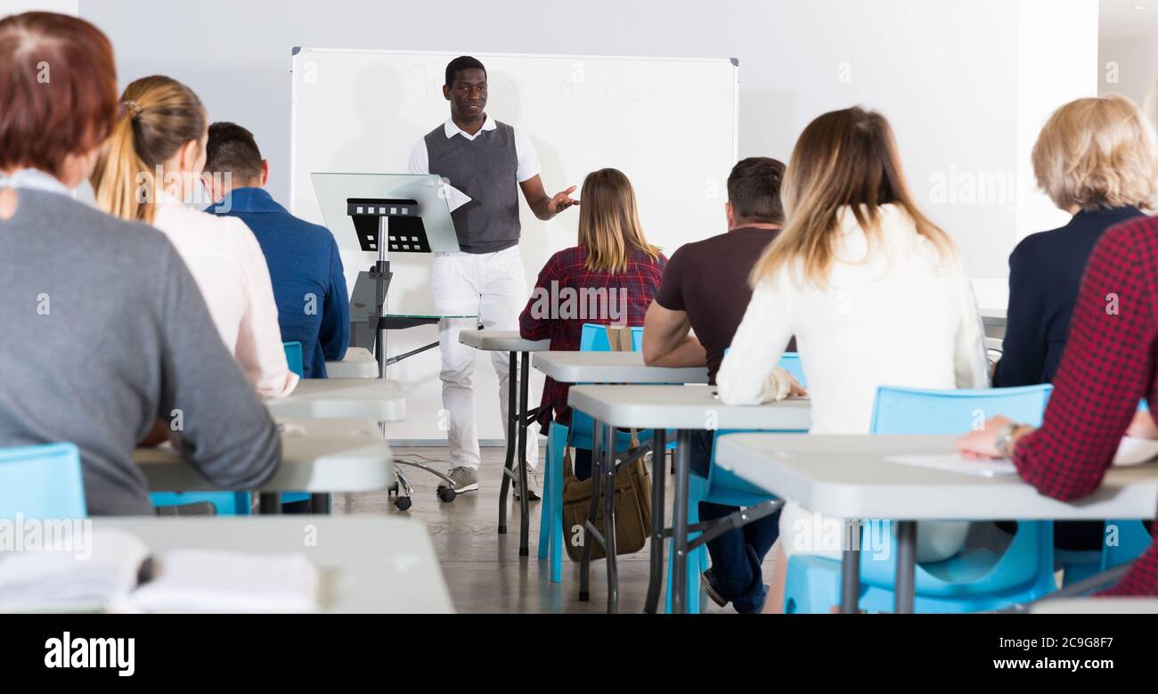 Smiling African American teacher giving presentation for students in ...
