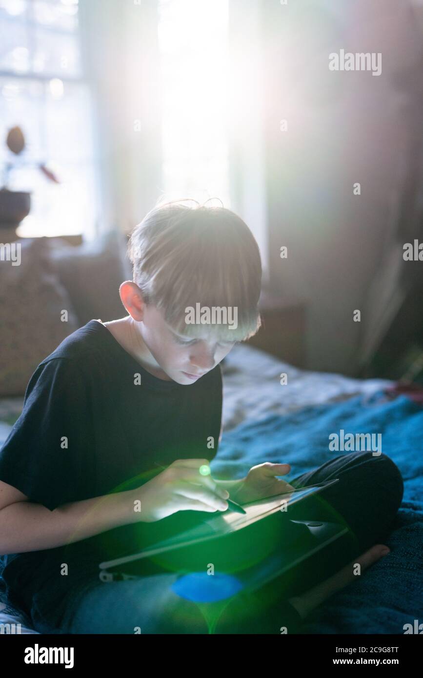 Tween drawing on tablet with stylus while sitting on bed inside Stock ...