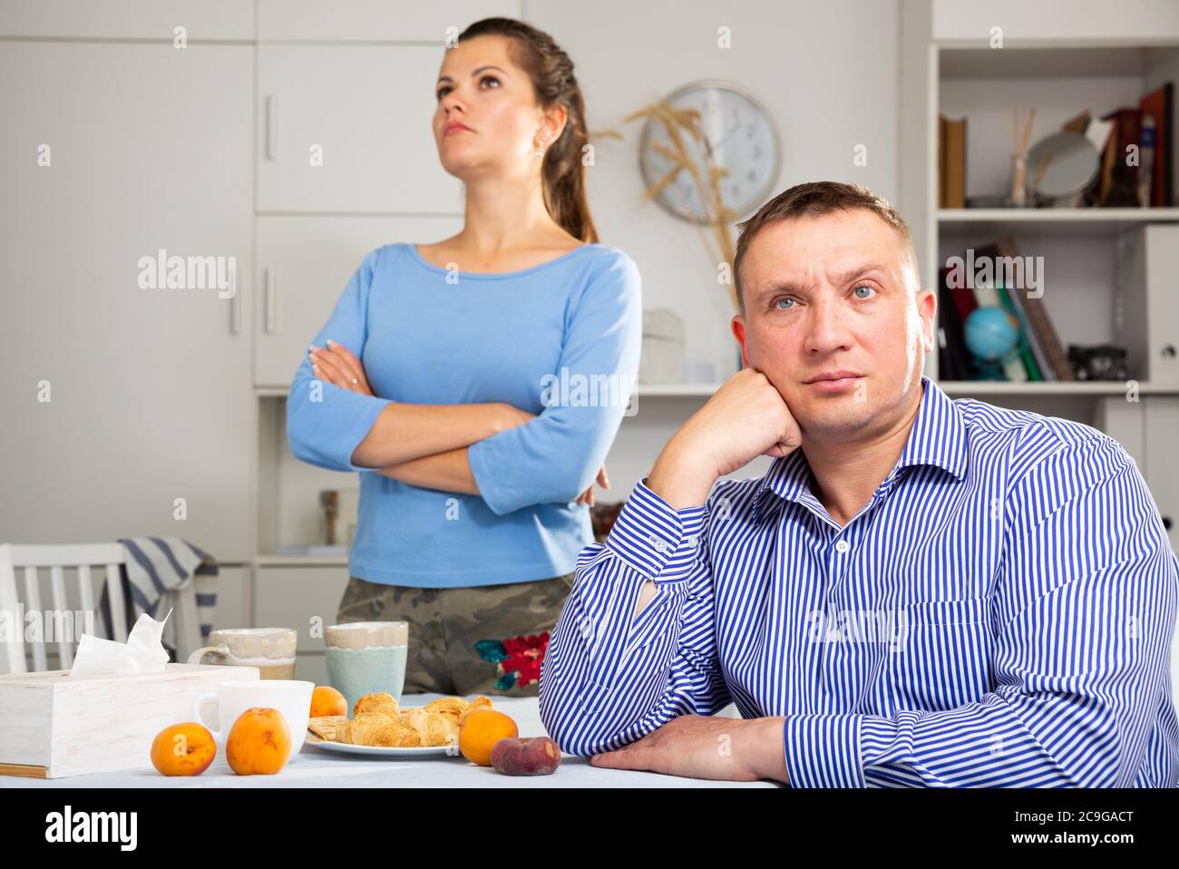 Upset man sitting at table after quarrel with wife at the home table ...