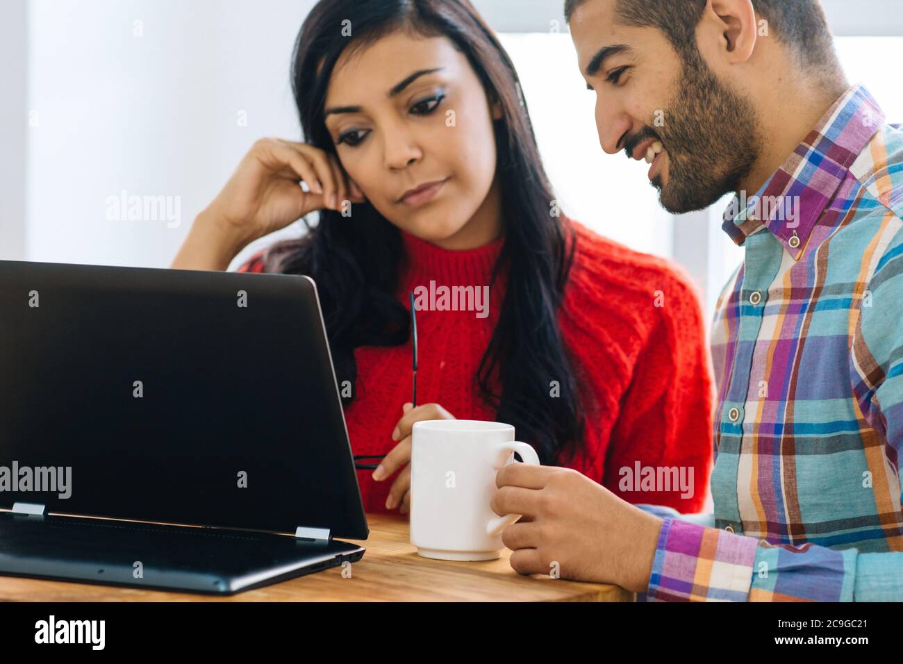 Couple of two young colleagues looking at a computer screen in an ...