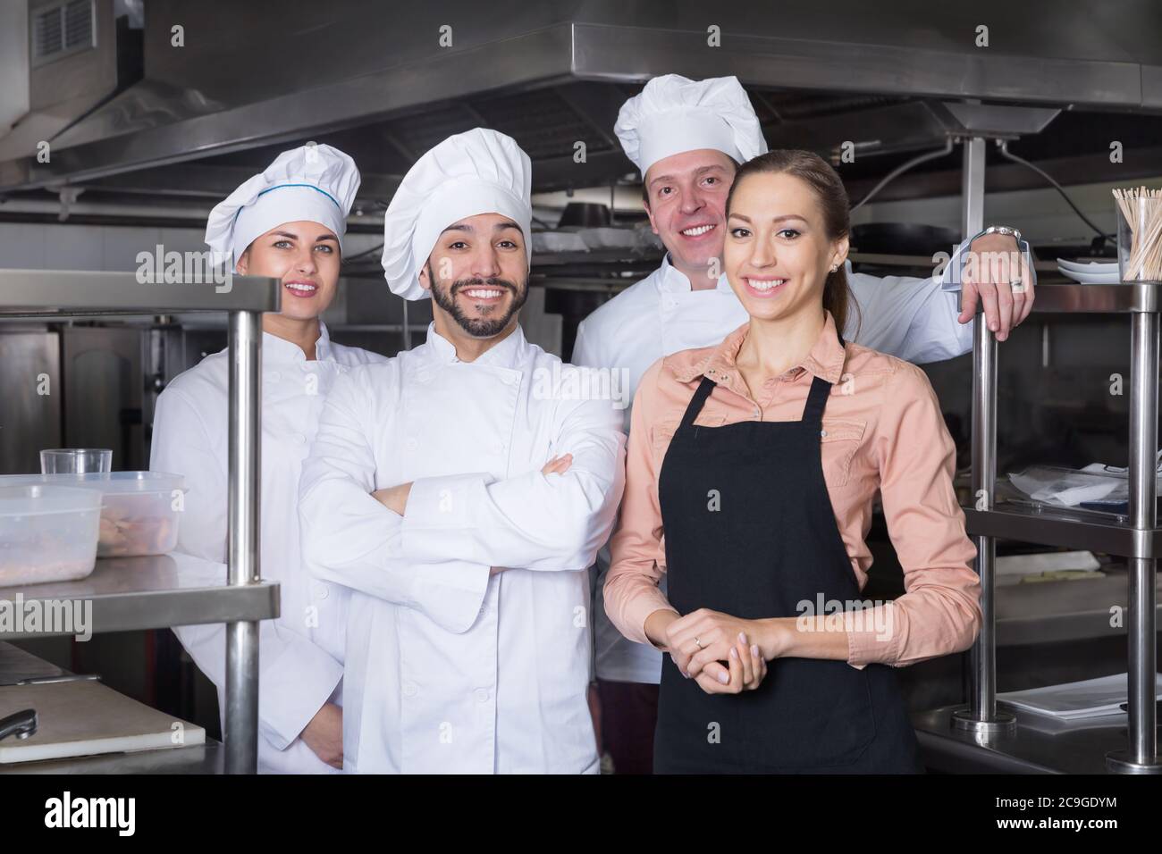 Team of restaurant staff posing together in modern professional kitchen ...