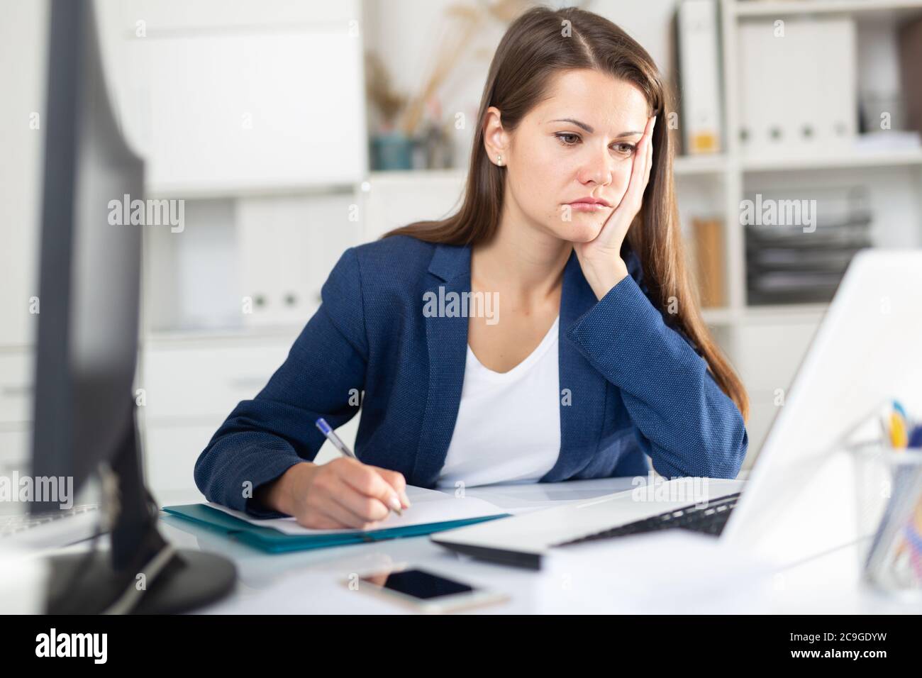 Portrait of disappointed female office employee during work with laptop ...