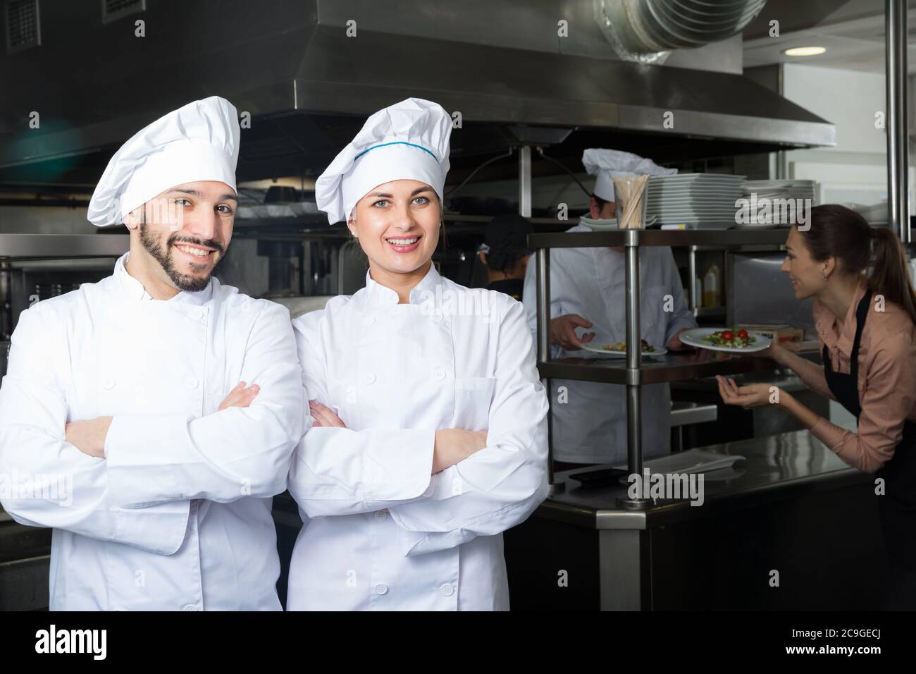 Portrait of two confident chefs posing with crossed arms in ...