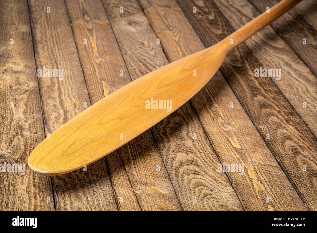 blade of wooden canoe paddle (beaver tail) against weathered wood ...