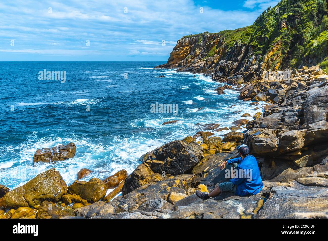 High angle shot of a male sitting on the shore and looking to the ...