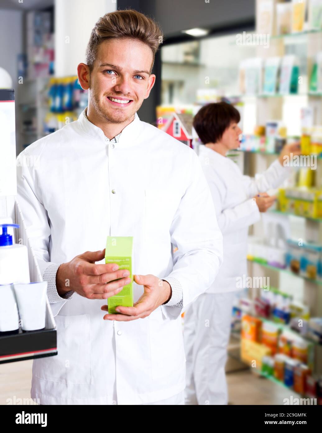Portrait of handsome man druggist in white coat giving advice to ...