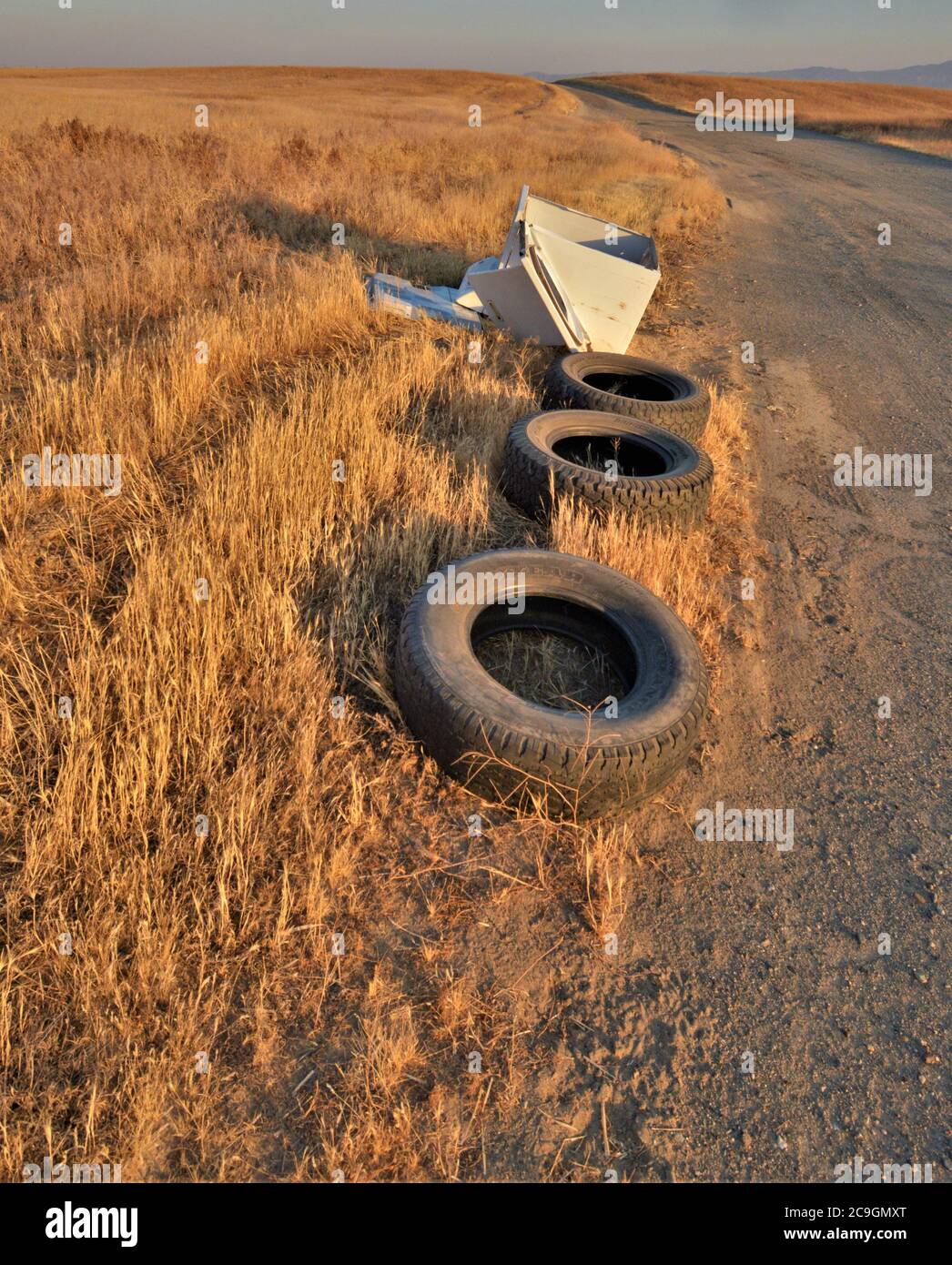 used junk tires dumped on the side of a farm road with a dryer in the ...
