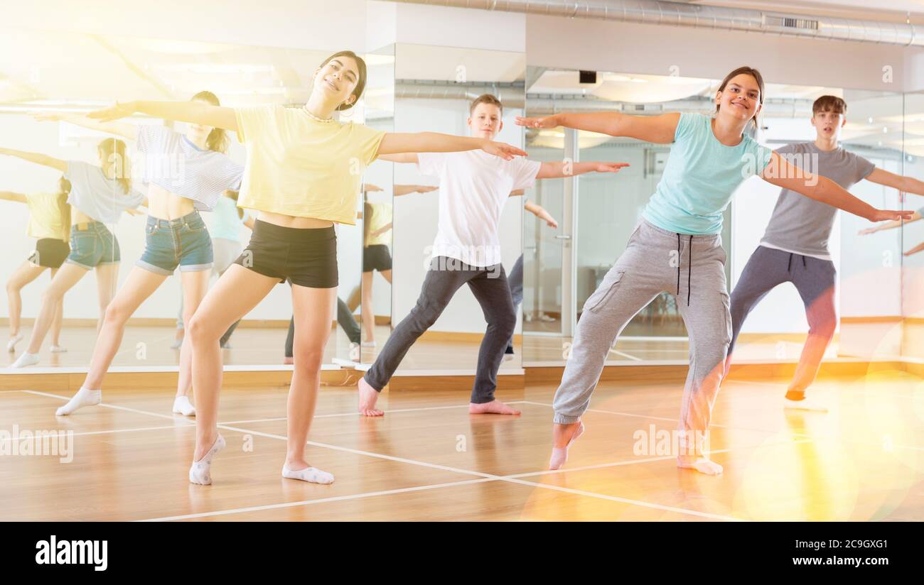 Teenagers in dance hall studying new movements, smiling and having fun ...