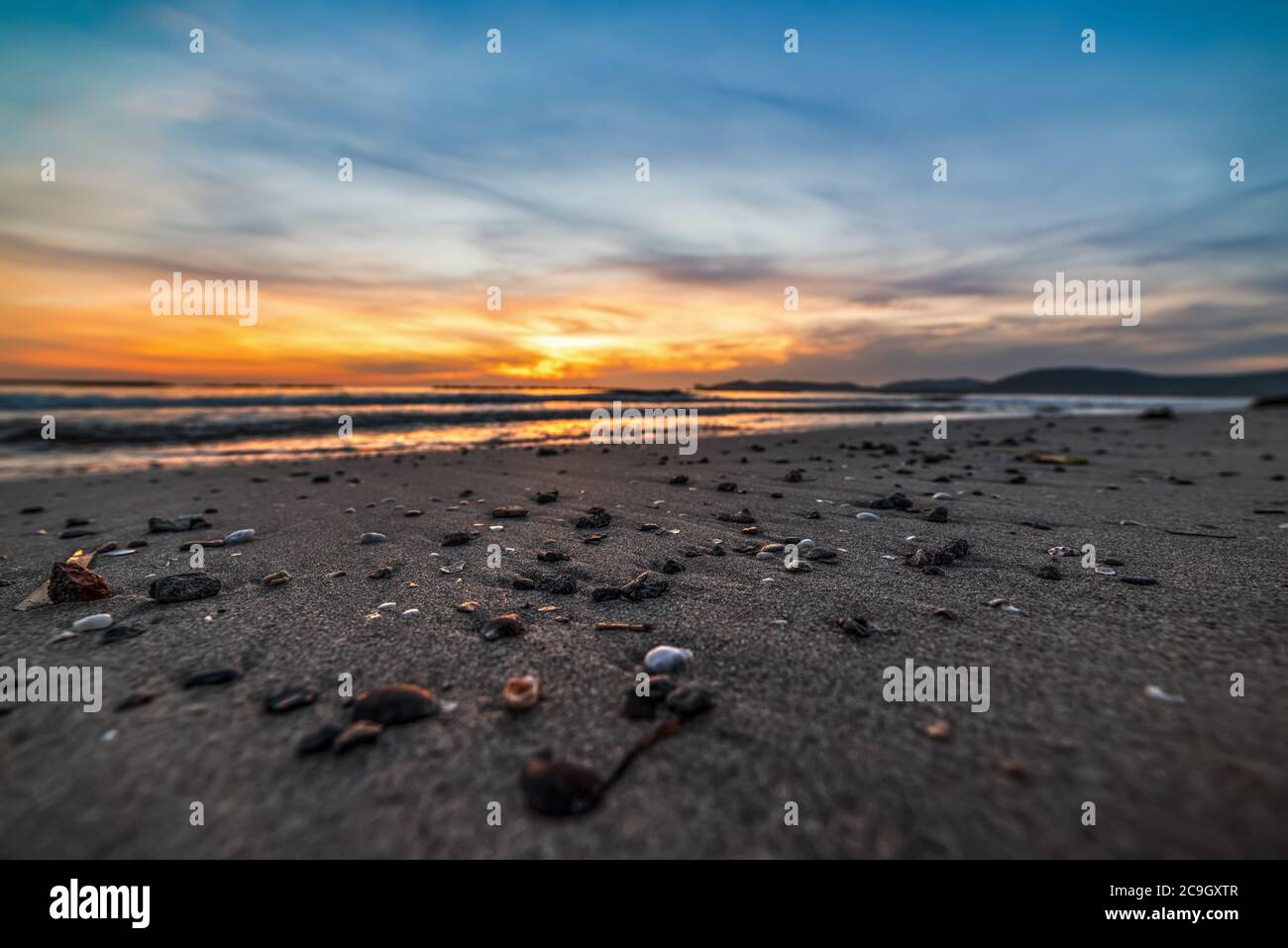 Shells and pebbles on the beach at sunset. Sardinia, Italy Stock Photo ...