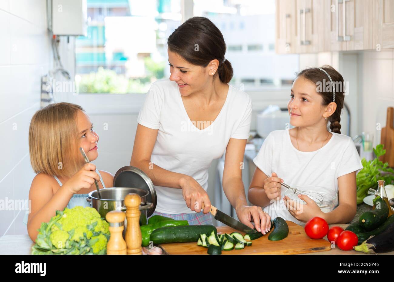 Two little girls helping mother in cooking at kitchen Stock Photo - Alamy