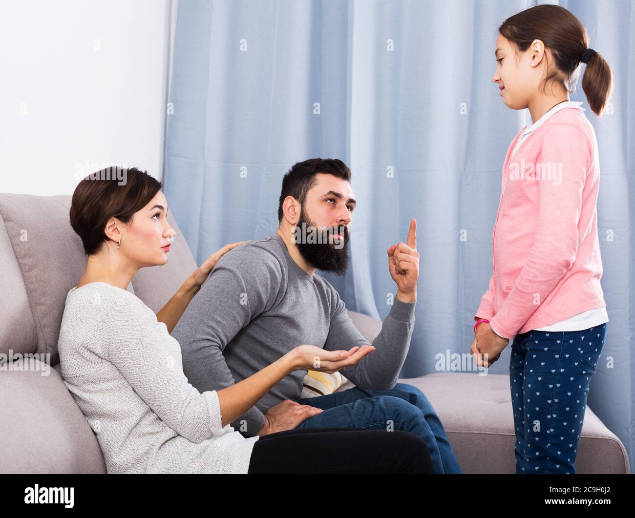 Young man and woman lecturing their daughter for bad behavior at home ...