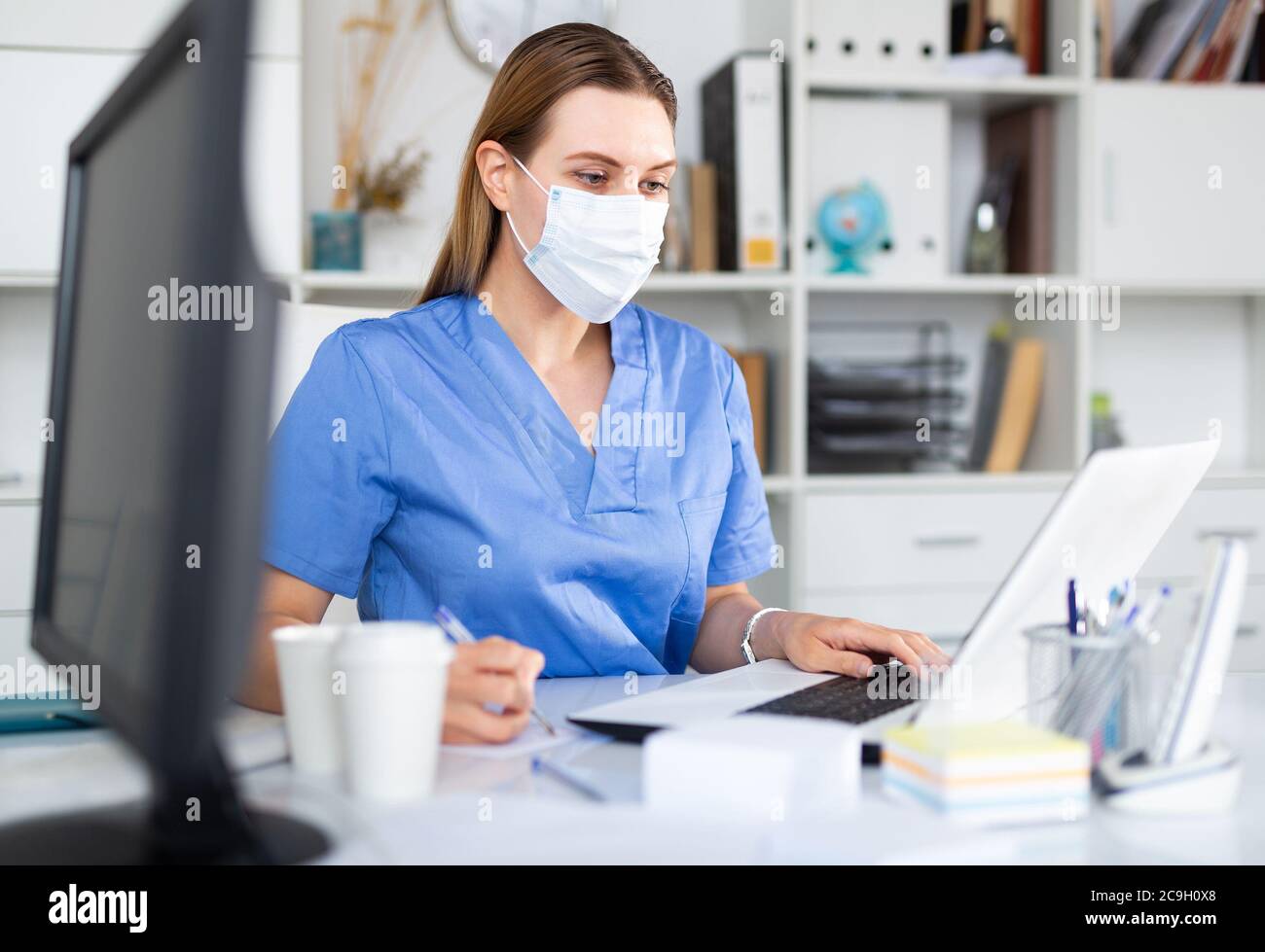 Medical female worker enters patient data into laptop Stock Photo - Alamy