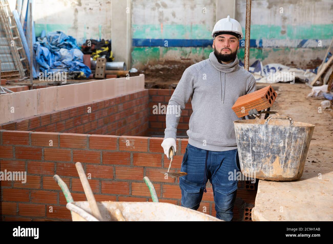 Focused young man working on his house renovations, installing brick ...