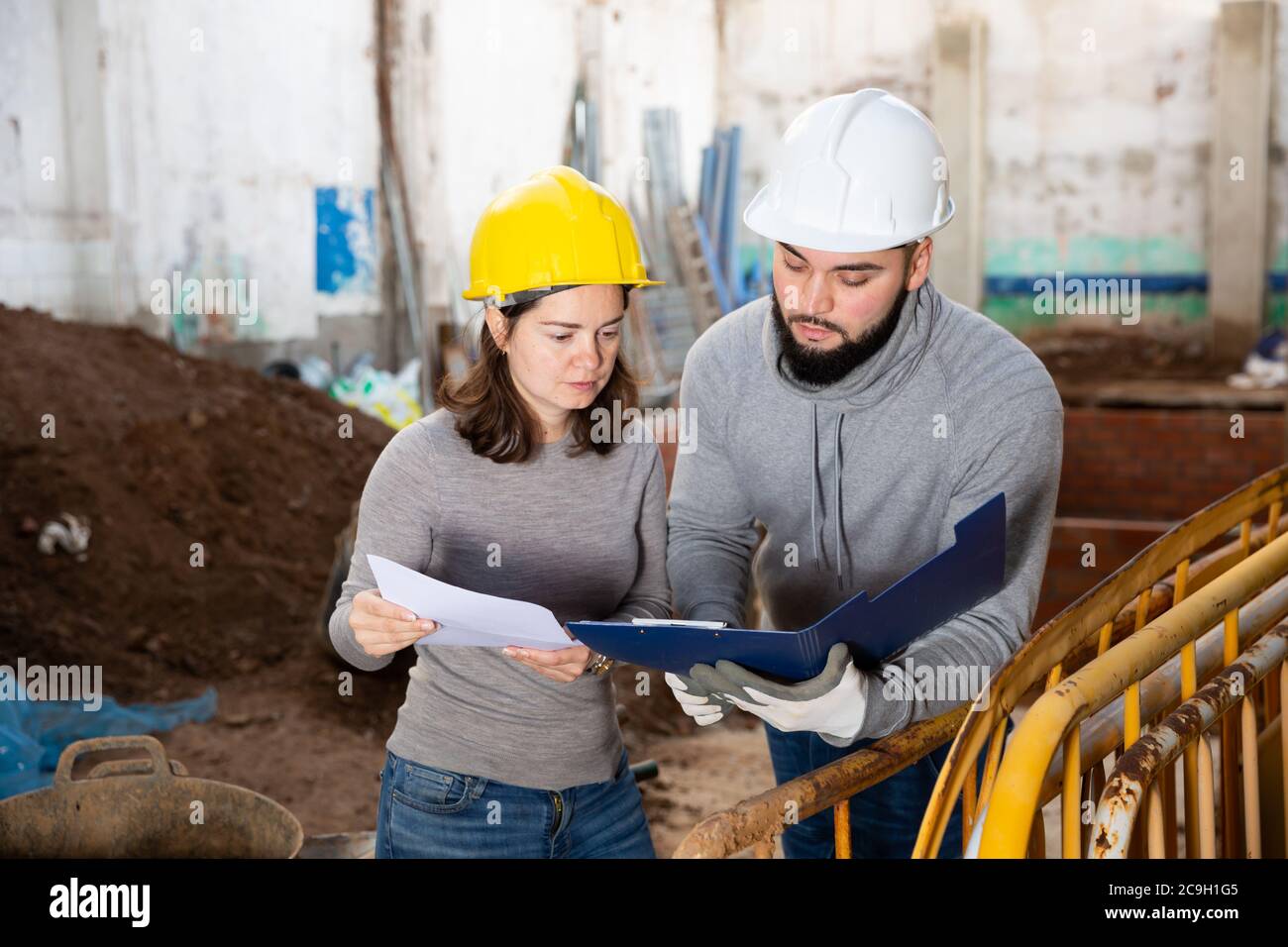 Civil engineers inspecting process of building overhaul, comparing to ...