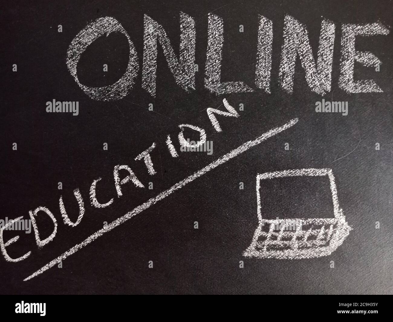 Online education word presented with laptop drawing art on chalkboard ...