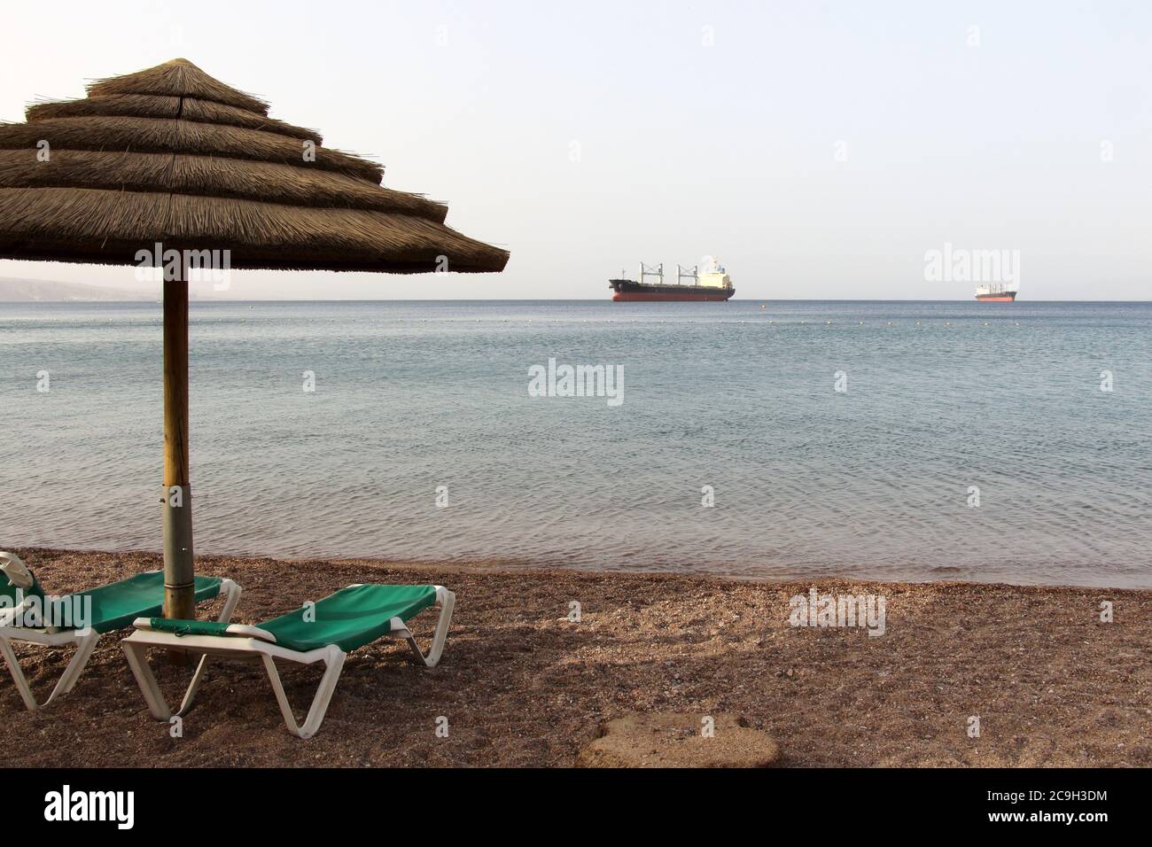 Morning on Eilat public beach. Large cargo Ship on horizon Stock Photo ...