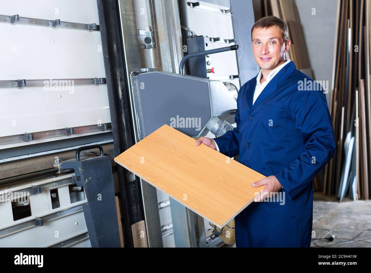 portrait of happy russian man in uniform working on large automatic saw ...