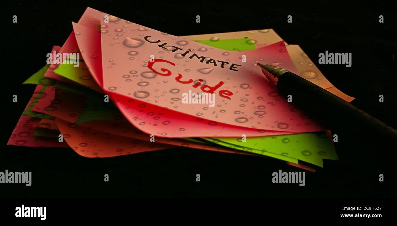 Ultimate guide word with hand written concept on colorful paper slip ...