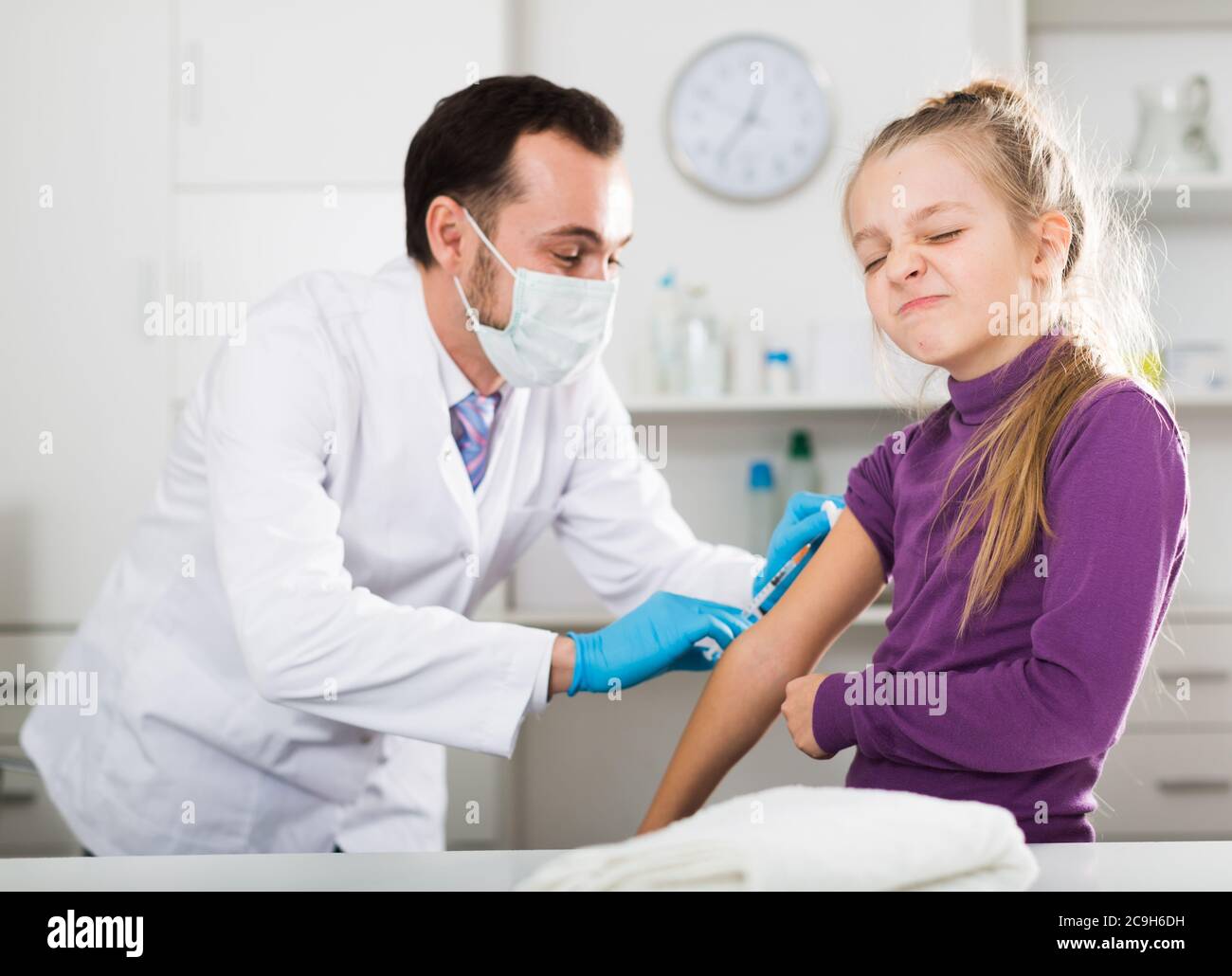 Male doctor using syringe to make injection to young female patient in ...