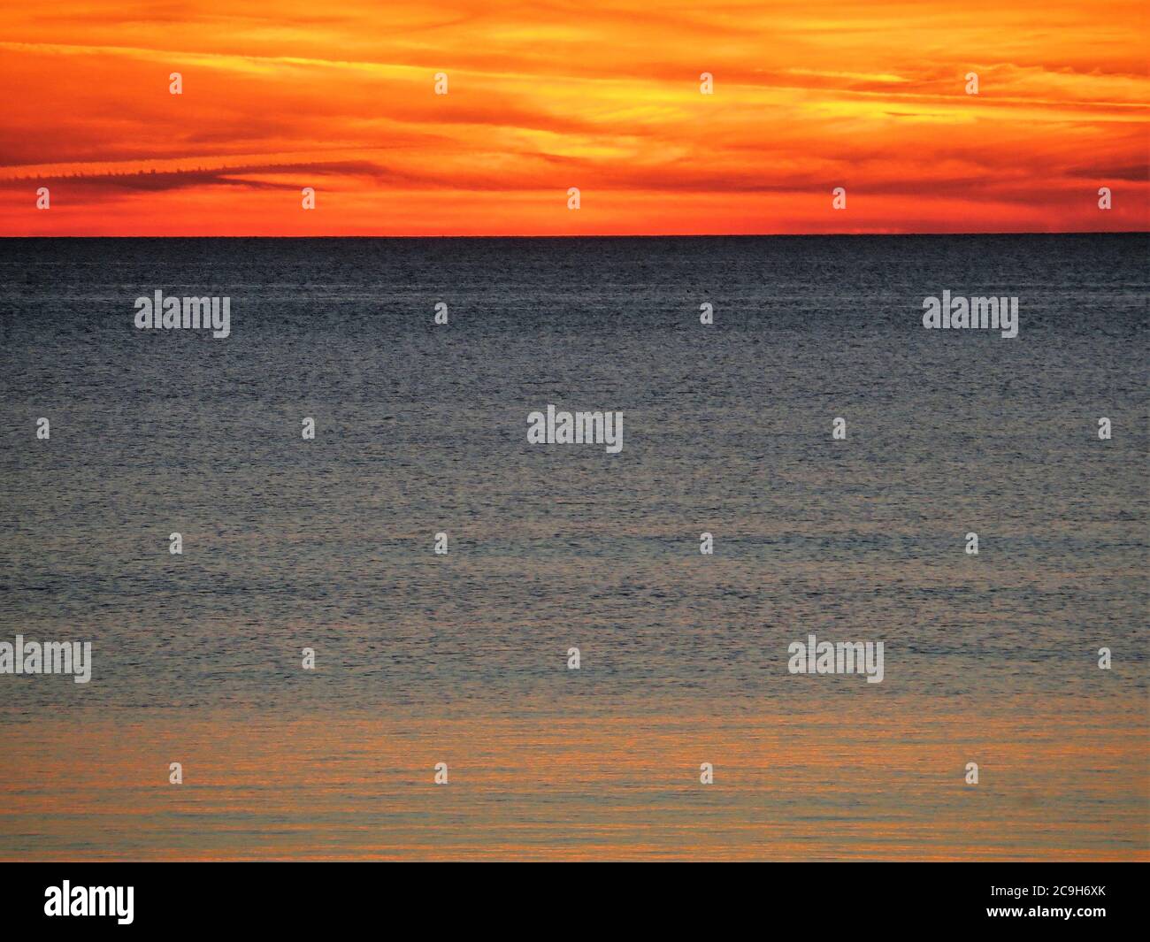 Orange Cloud Horizon with Calm Blue Water and Light Orange Reflection ...