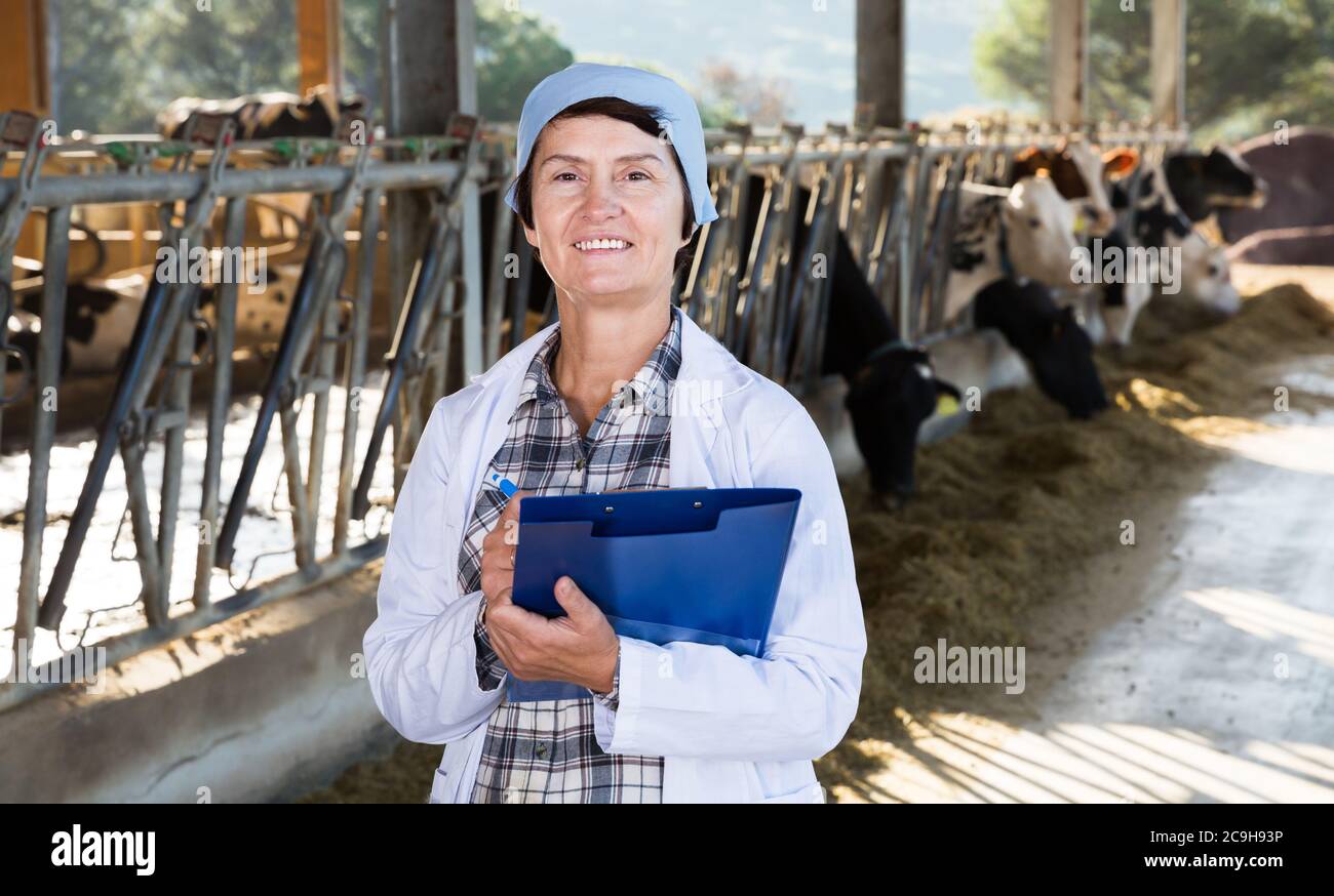 Portrait of female quality expert who is standing in uniform at the cow ...
