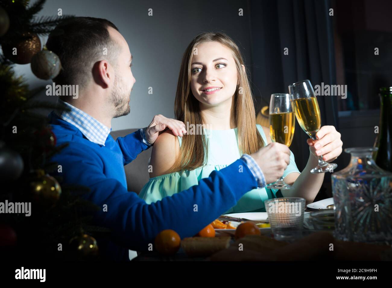 Smiling loving couple celebrating New Year, giving toasts and enjoying dinner at home Stock ...