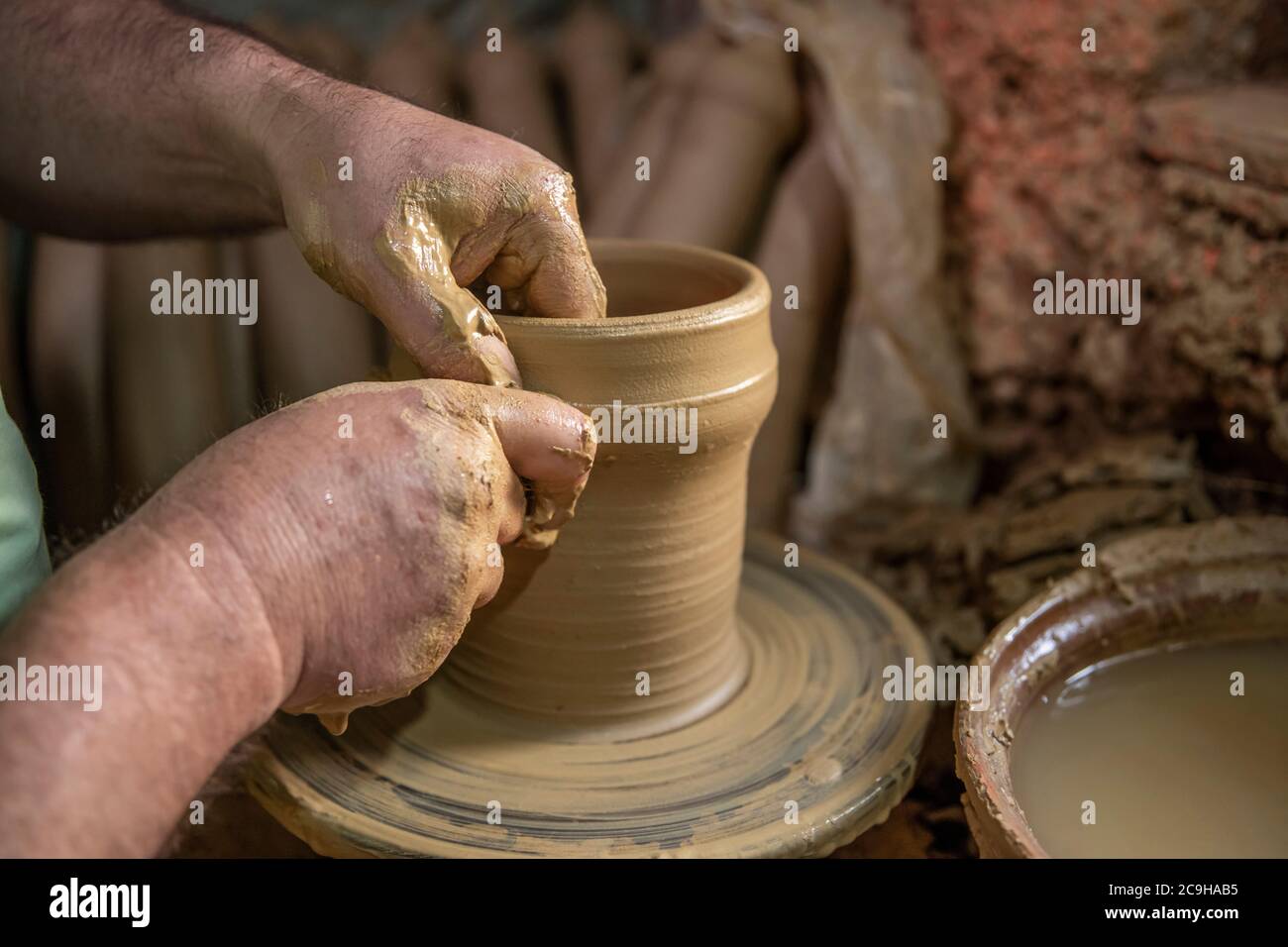 Male potter makes a pot on the pottery wheel. Terracotta pottery guy on ...