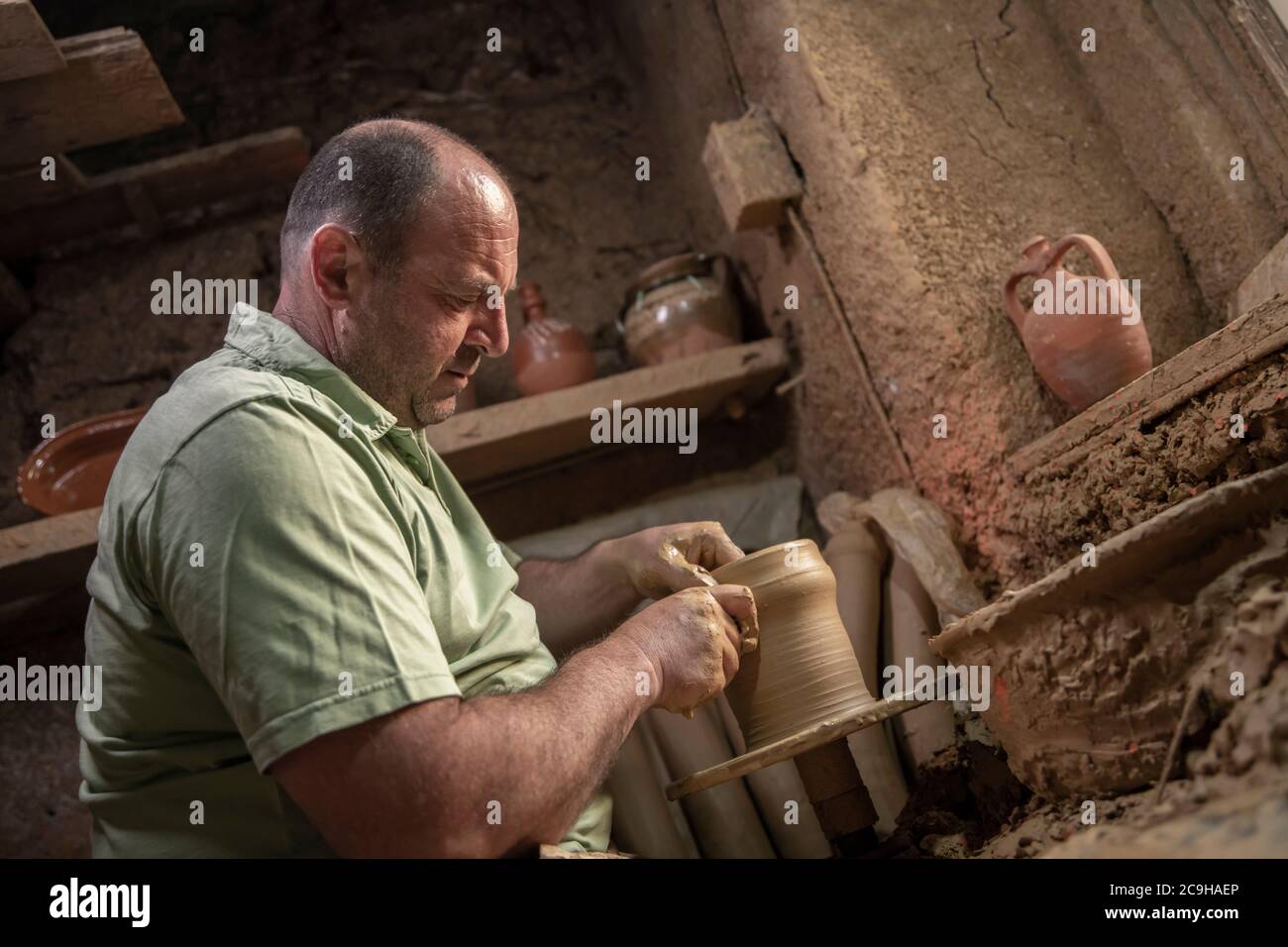 Male potter makes a pot on the pottery wheel. Terracotta pottery guy on ...