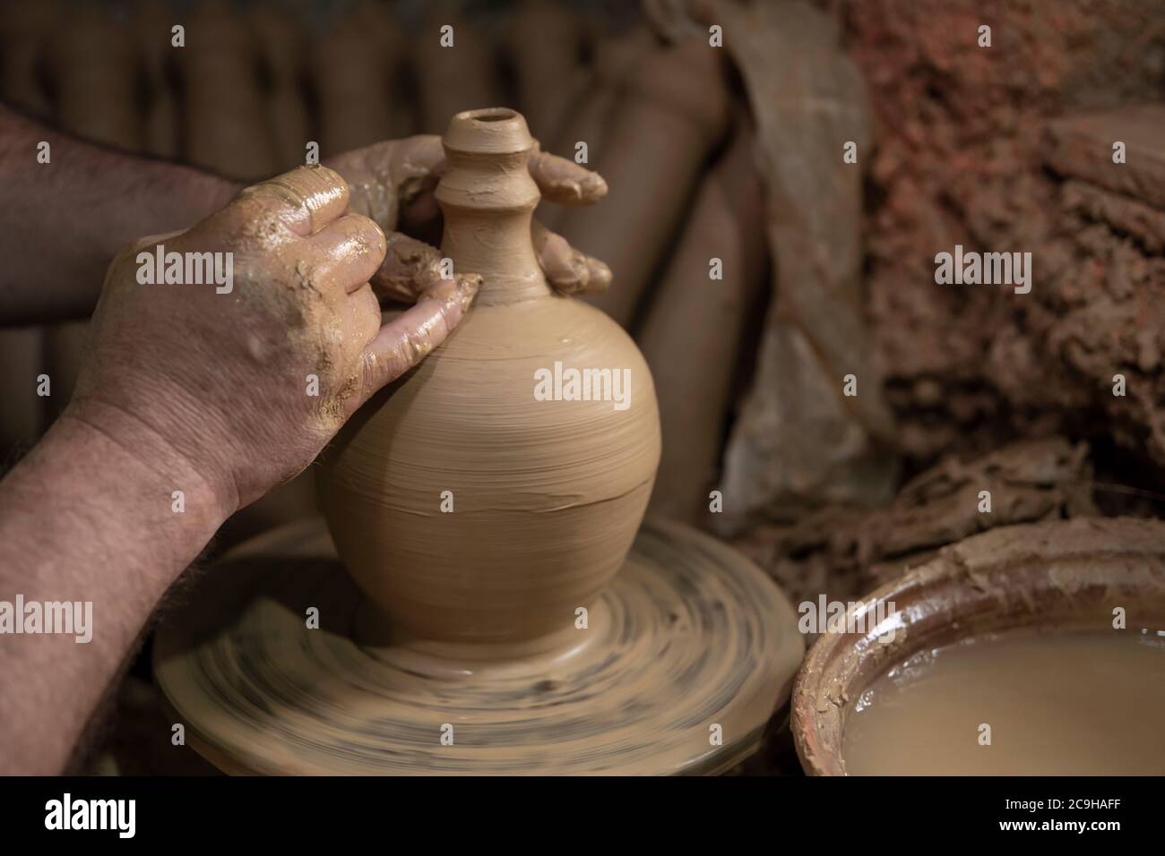 Male potter makes a pot on the pottery wheel. Terracotta pottery guy on ...
