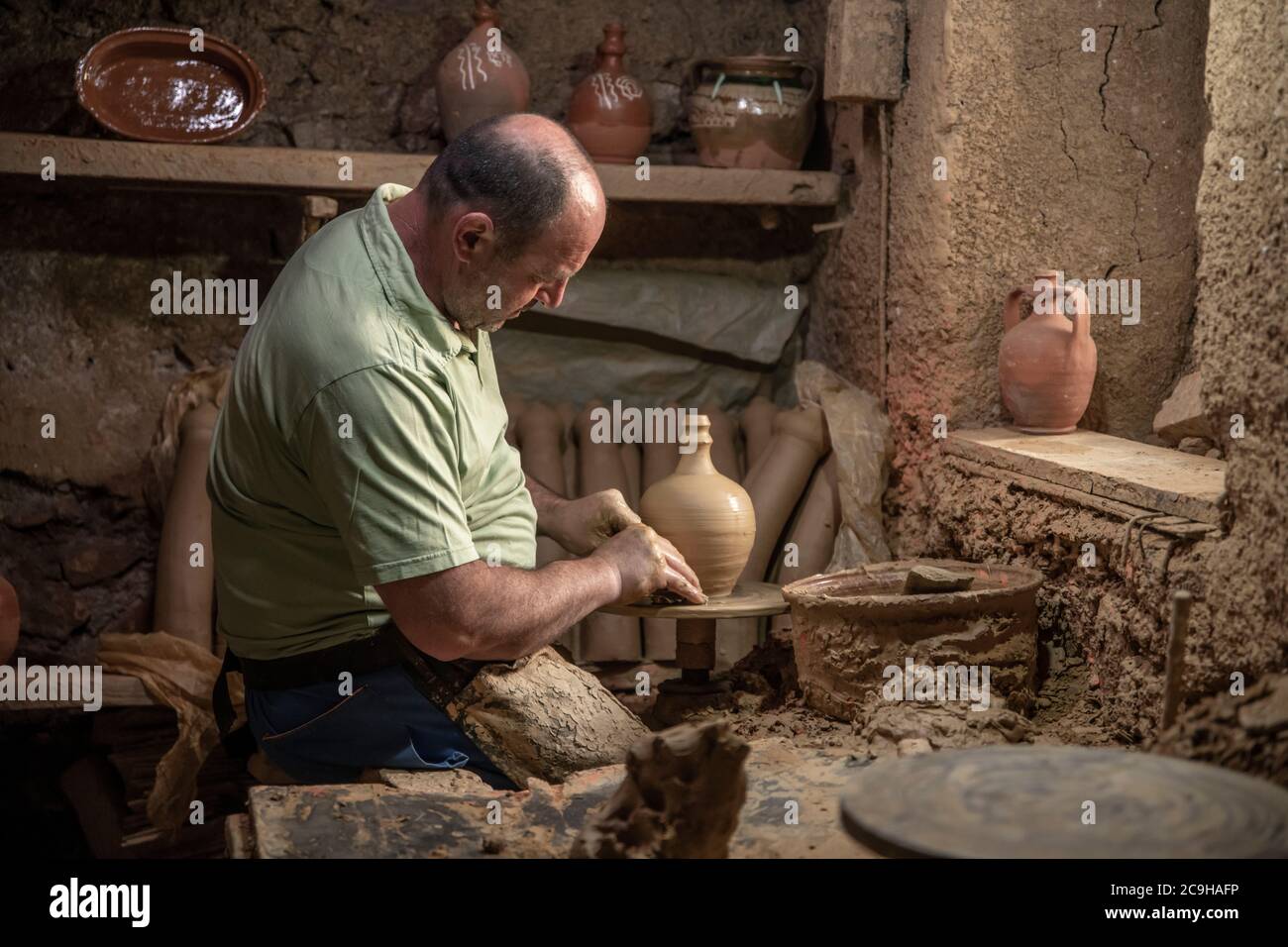 Male potter makes a pot on the pottery wheel. Terracotta pottery guy on ...
