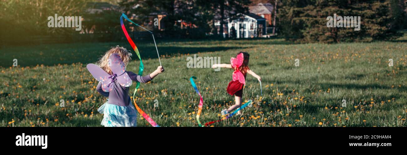 Children girls playing with ribbons in park. Kids running on meadow ...