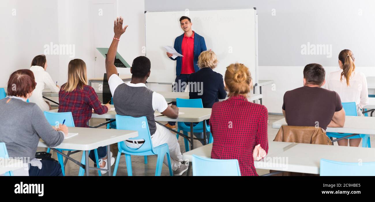 Friendly male teacher lecturing to attentive adult students at ...